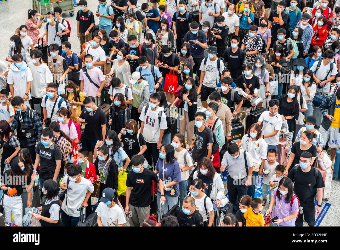 Crowds of Chinese travelers wearing protective masks wait in queues at ...