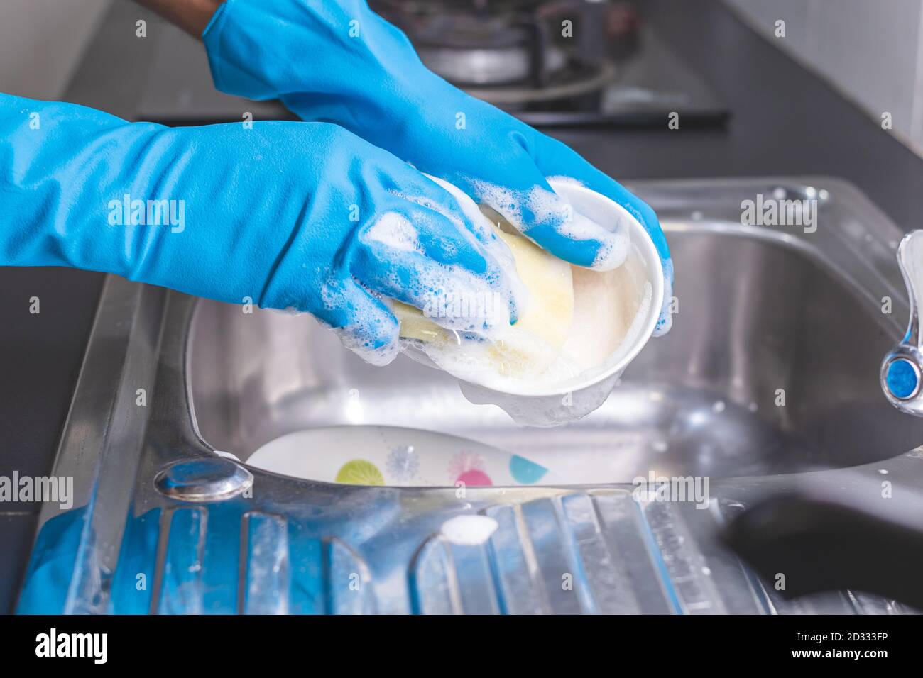 Close up of a man wearing a blue rubber glove was washing the cup with ...