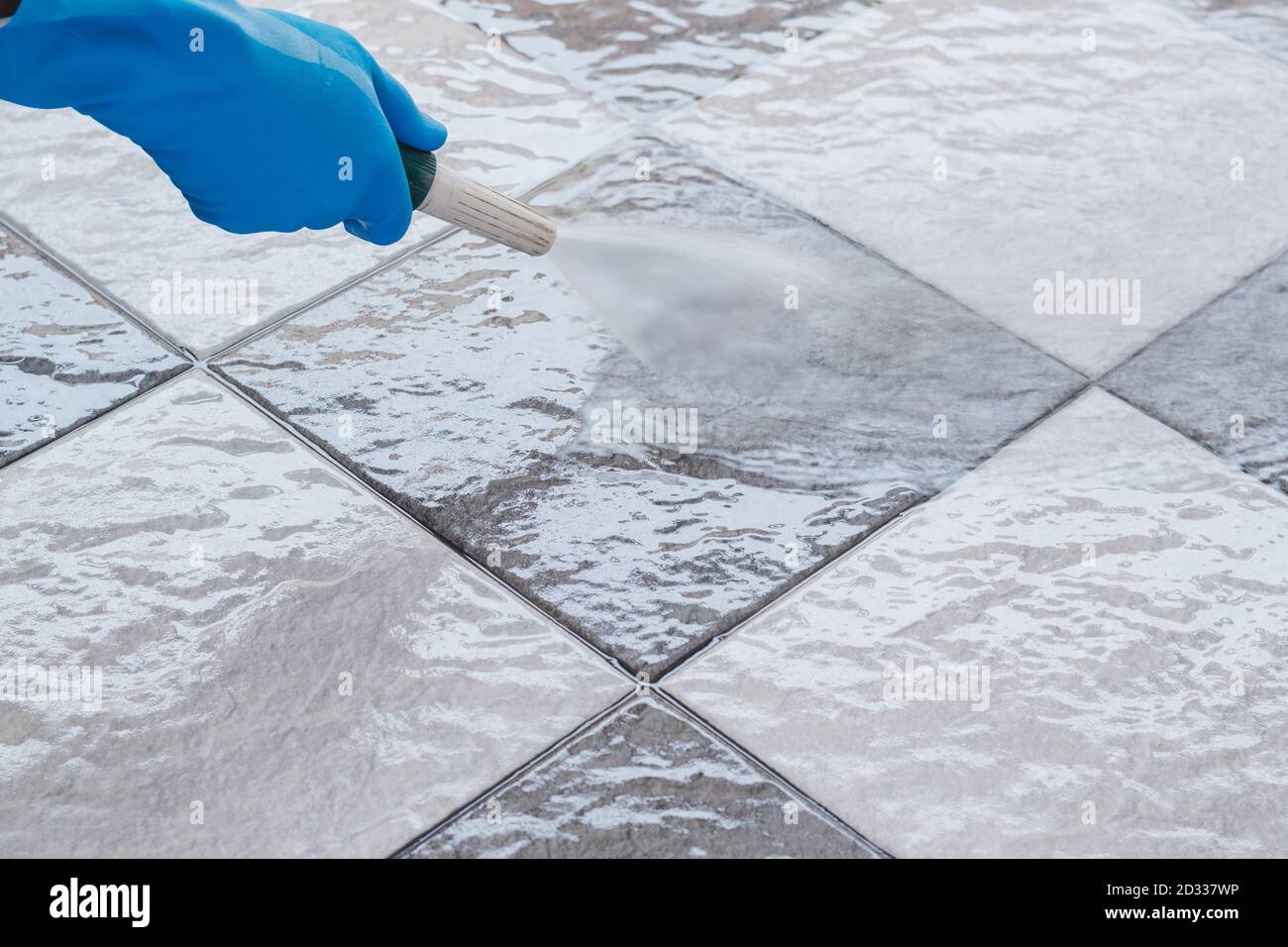 Hand of man wearing blue rubber gloves using a hose to cleaning the ...