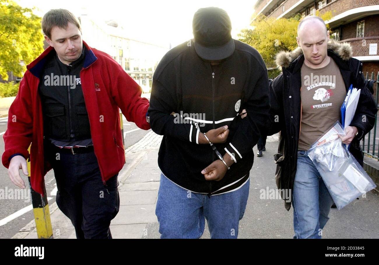 Police officers lead away a suspect, during a wave of dawn raids ...