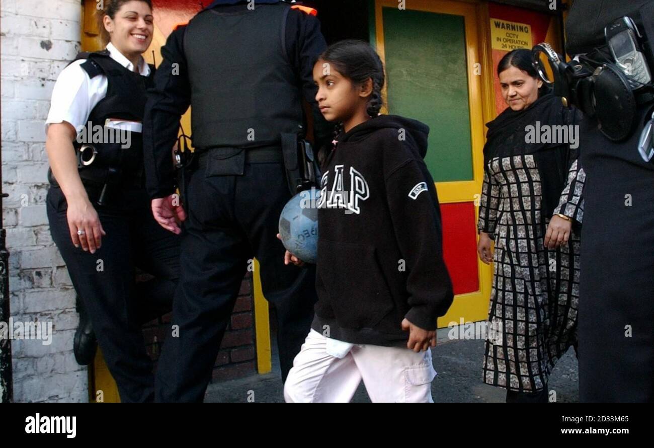 A young Asian girl walks past Police Officers during a raid on a ...
