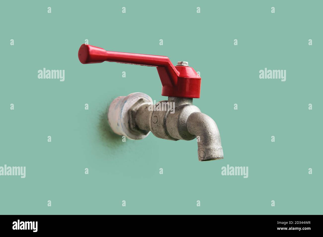 Closeup the tap, red handle that is embedded in the pastel color wall ...