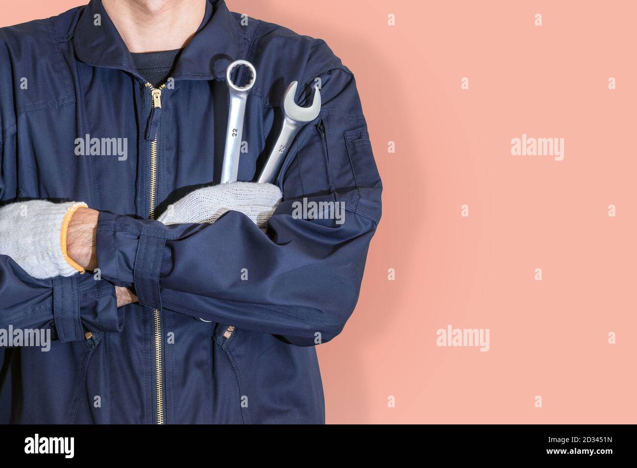 Car repairman wearing a dark blue uniform standing and holding a wrench ...