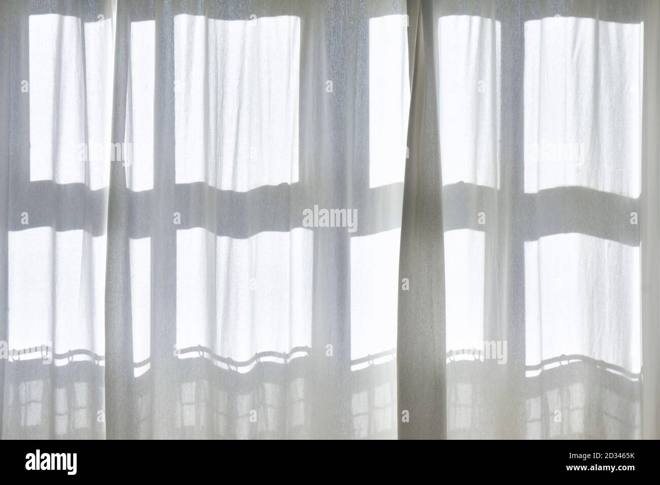 Morning sun shines through white transparent curtains with shadows from ...