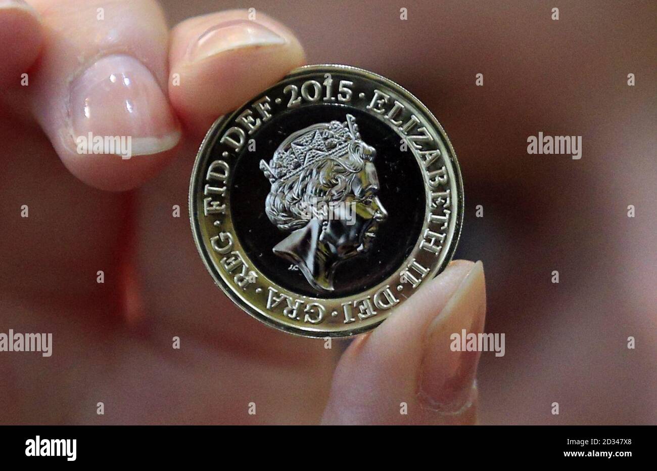 An event assistant from The Royal Mint holds a new two pound coin in ...