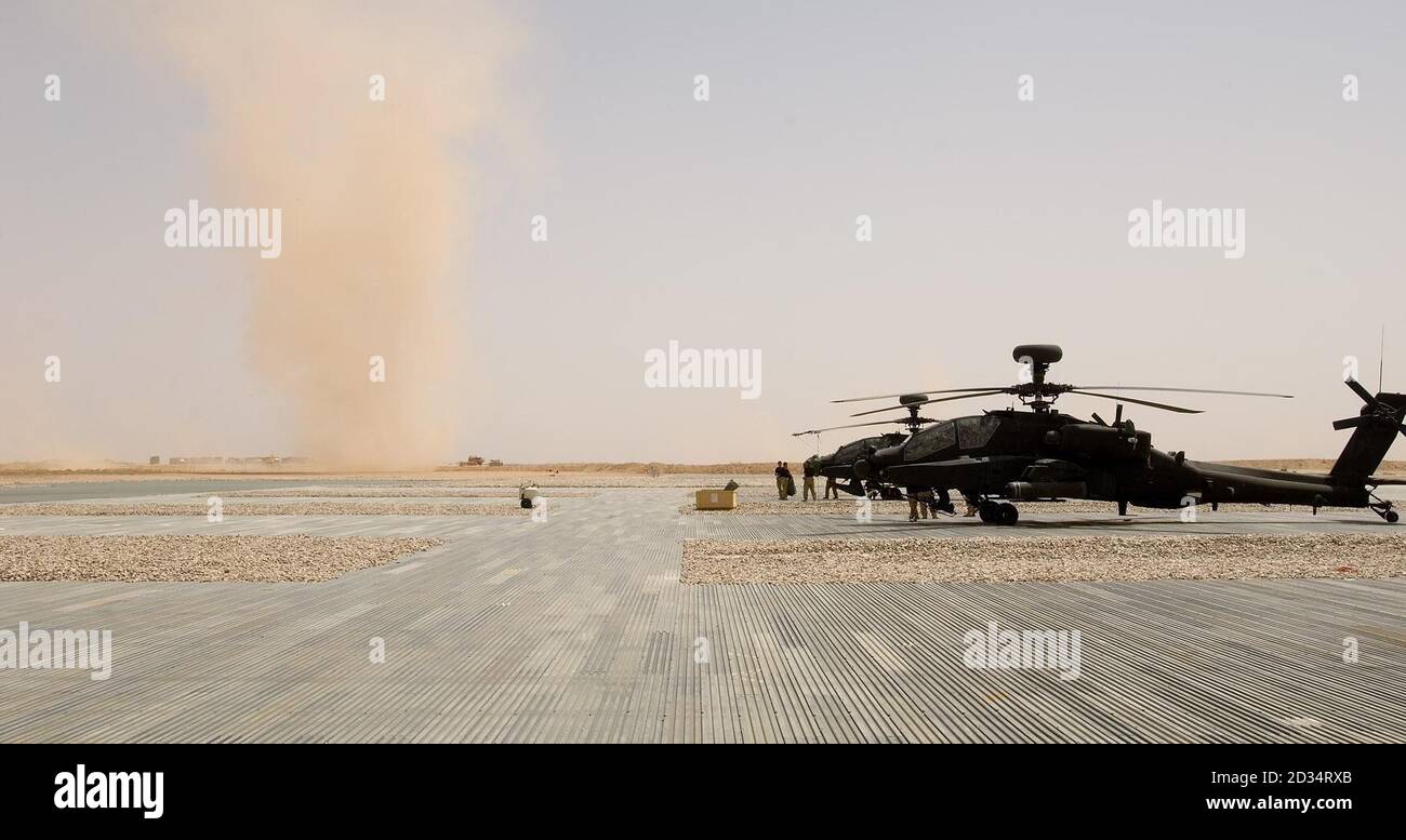 A dust-devil sweeps past parked British AH-64 Apache Attack Helicopters ...