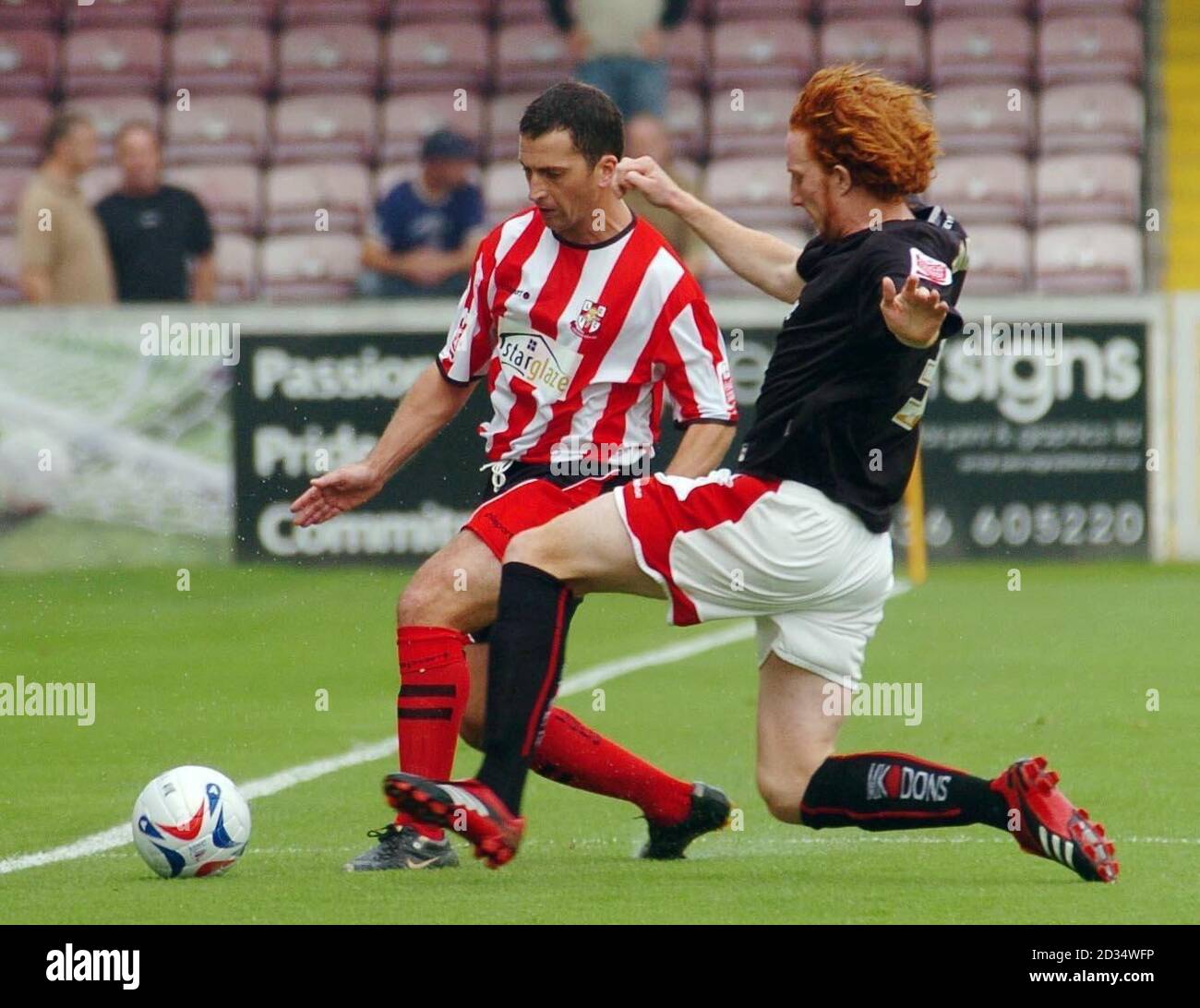 Lincoln's Nicky Eaden (left) tussles with MK Dons' Dean Lewington ...