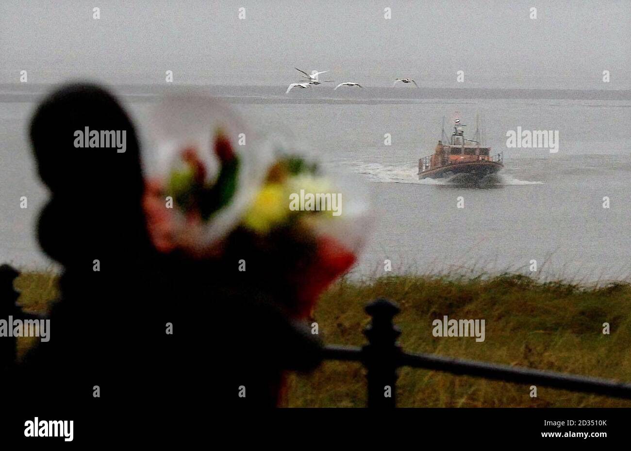 Flowers placed on a seaman's statue in the foreground, with the ...