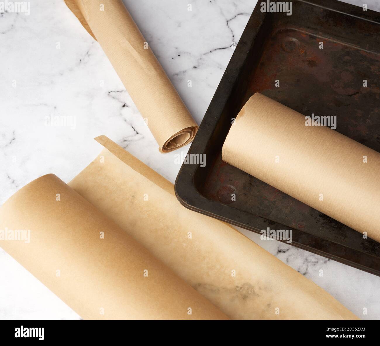 metal pan and rolls of brown parchment paper on a white table, top view ...