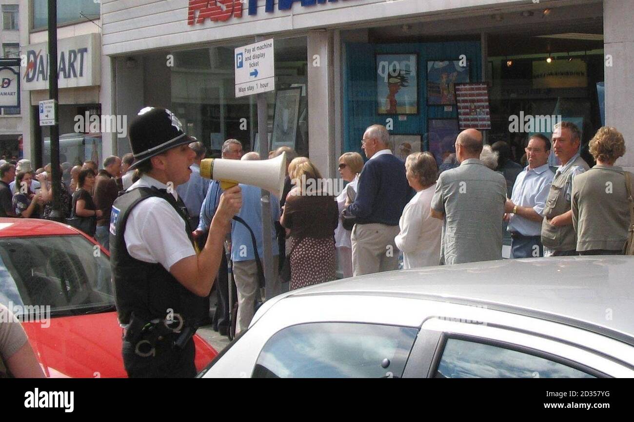 A police officer controls crowds as hundreds of Northern Rock customers ...