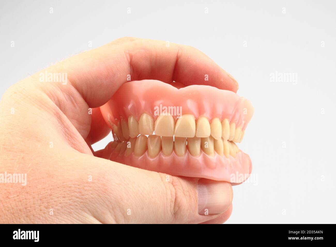 teeth prosthesis in the human hand isolated on the white background ...