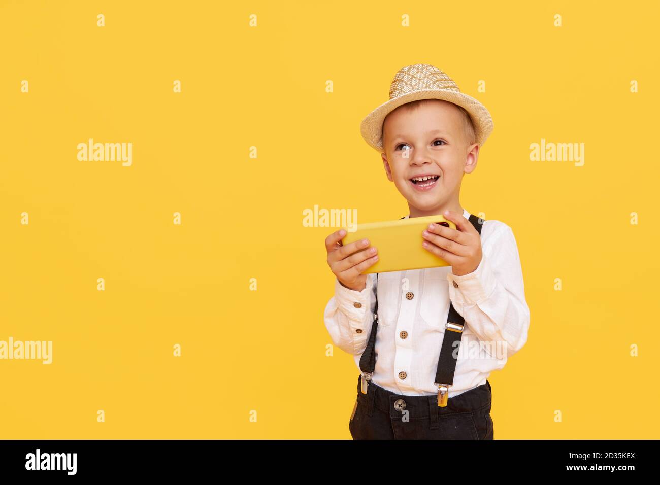 Cute smilling child boy with smartphone on yellow background ...