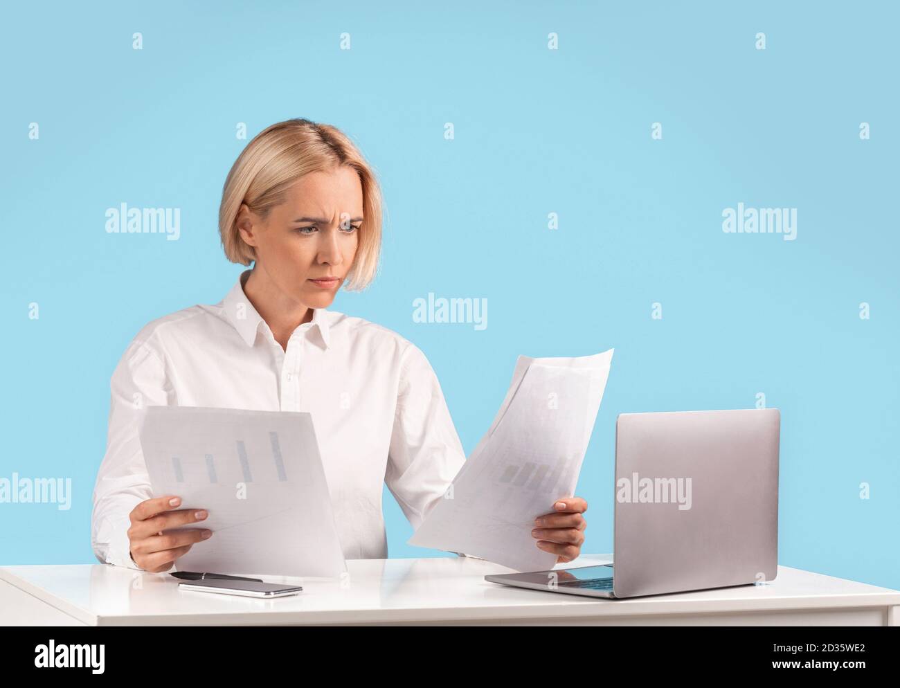 Focused business lady working with documents near laptop computer at ...