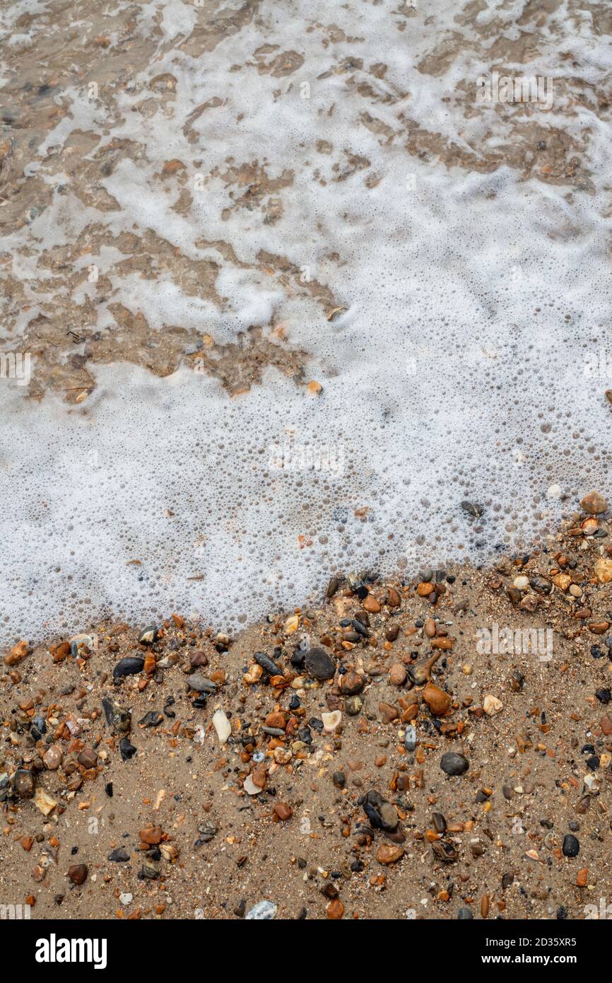 Foaming seawater breaking on sandy beach Stock Photo - Alamy