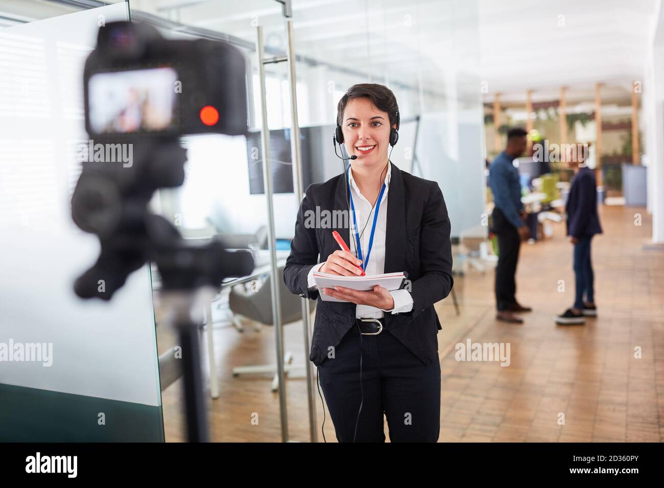 Young business woman in front of a video camera for an online tutorial ...