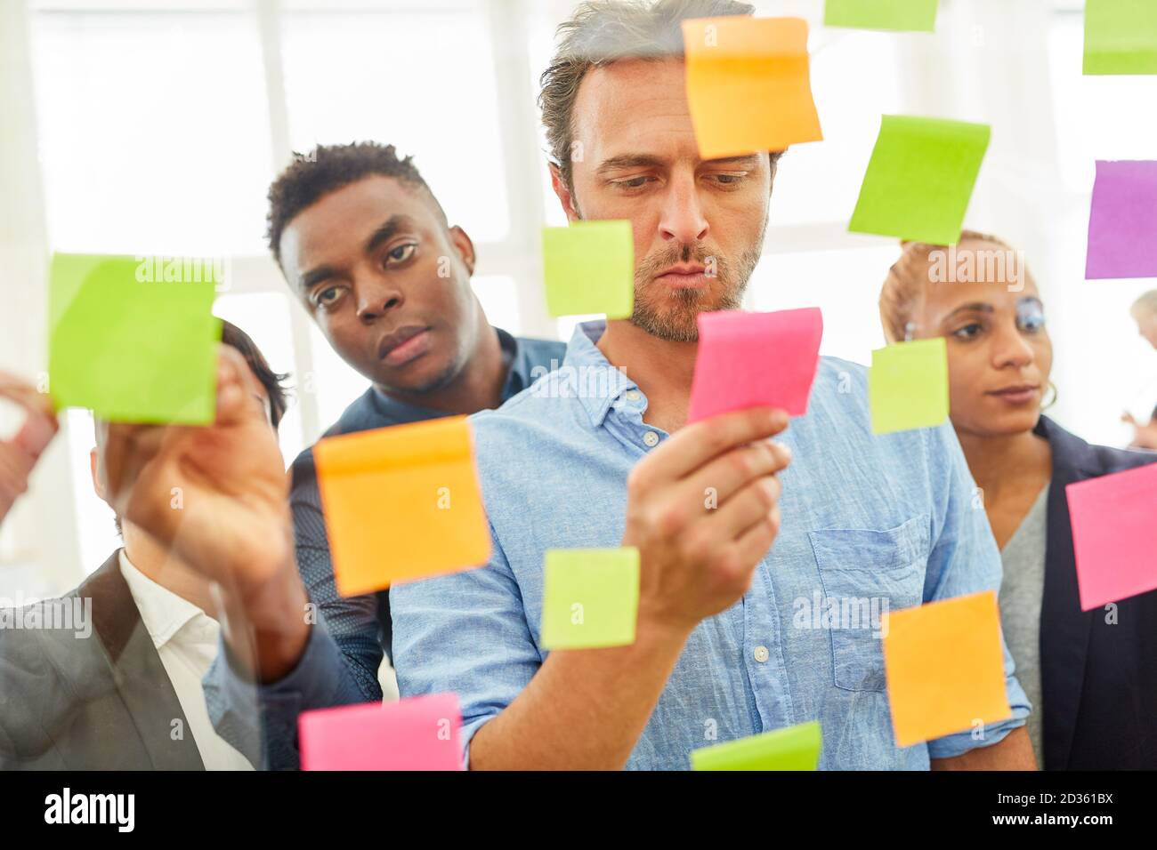 Start-up team analyzes sticky notes on the glass in a creative ...