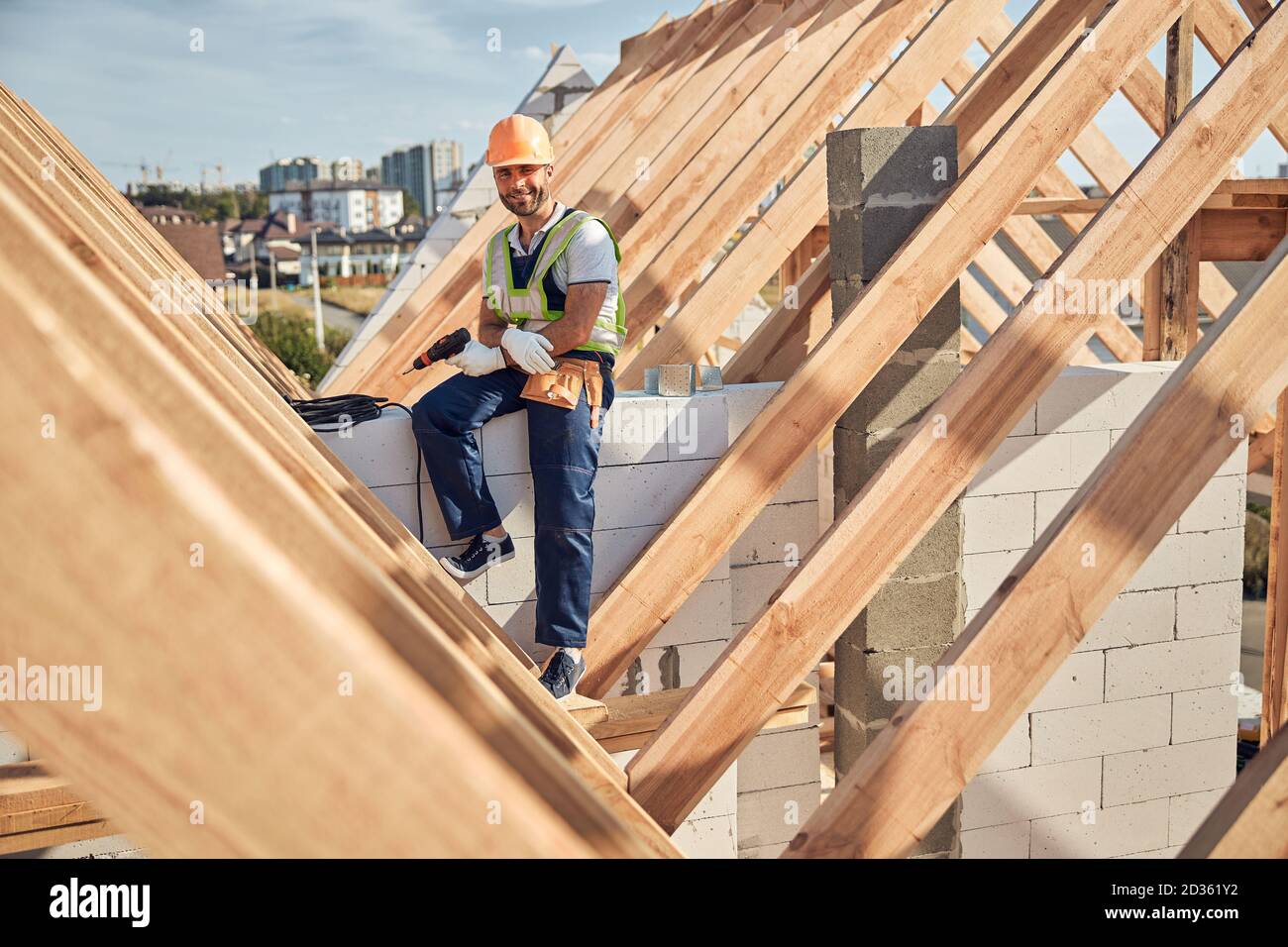 Smiley builder in a hard hat holding a drill driver Stock Photo - Alamy