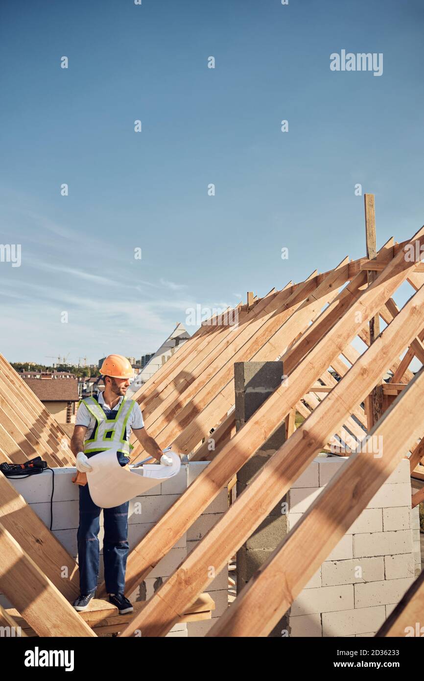 Competent foreman checking a blueprint and standing on the roof Stock ...