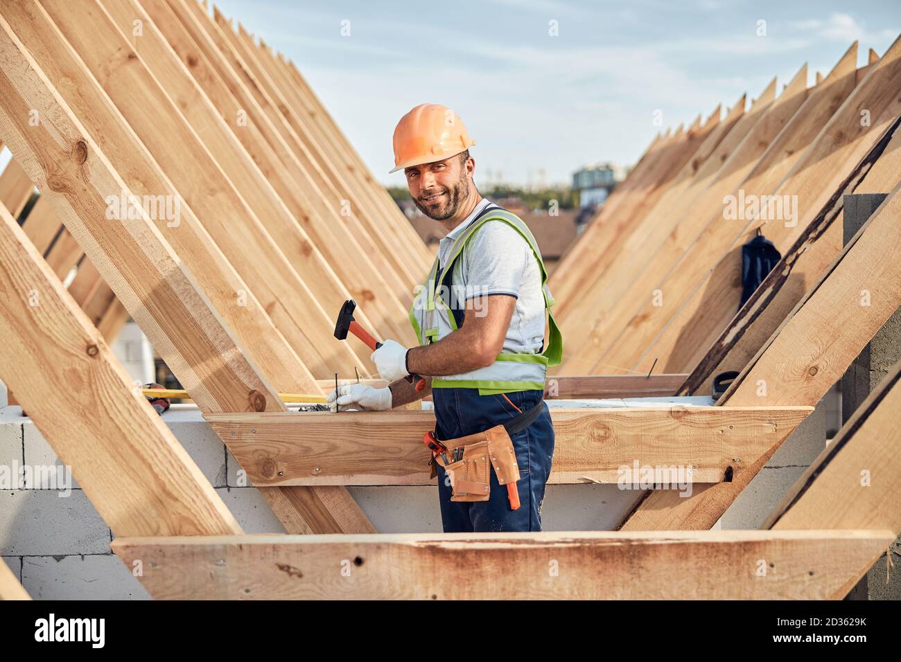 Smiley builder using a hammer at a construction site Stock Photo - Alamy