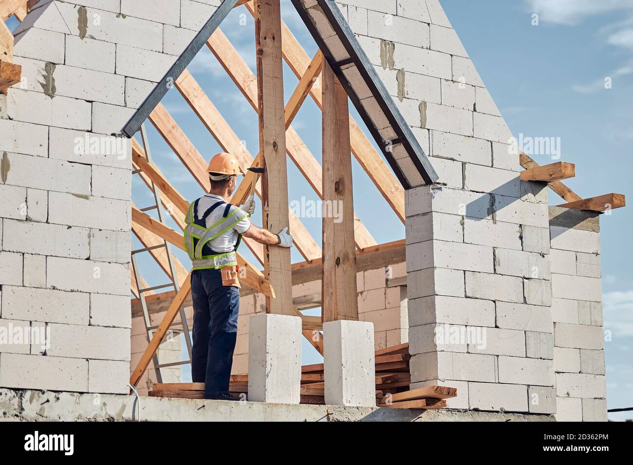Concentrated man in safety gear building a house Stock Photo - Alamy