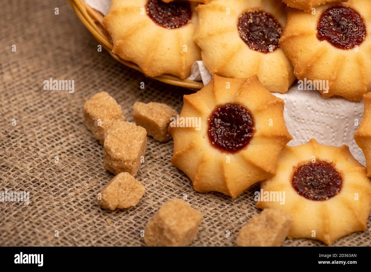 Homemade pastry cookies with jam and pieces of brown cane sugar on a ...