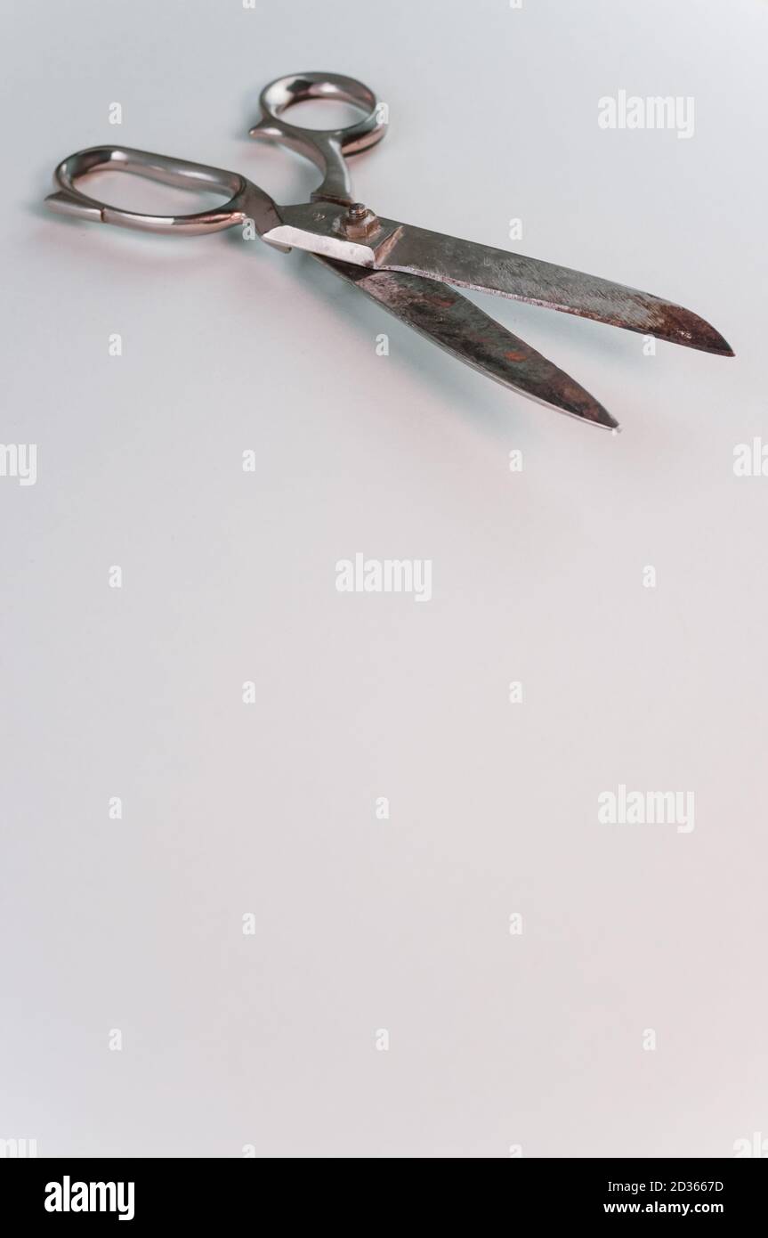 Vertical shot of old grunge carbon steel scissors on a white surface ...