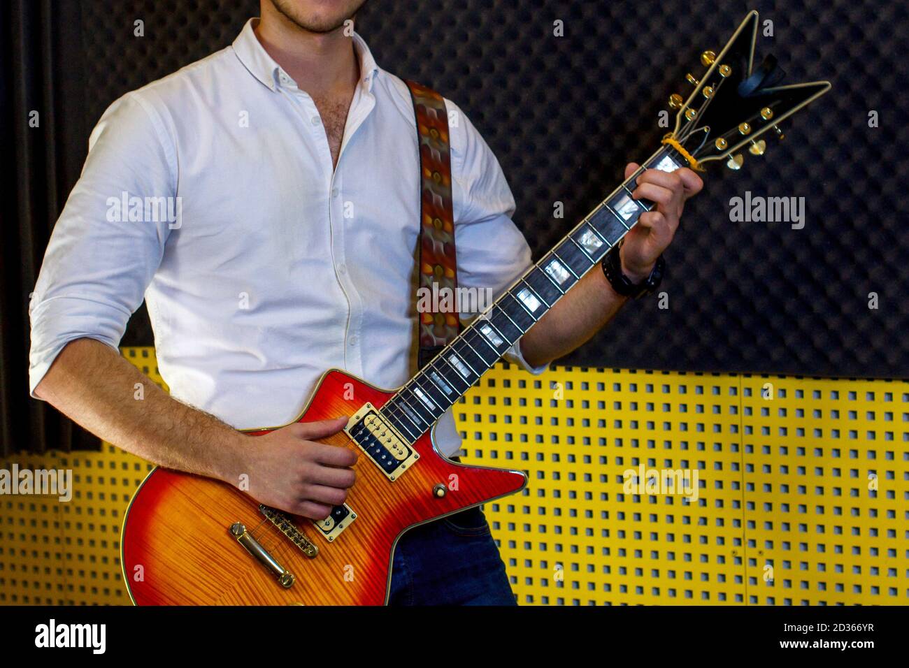 A guy in a white shirt with an electric guitar stands on the recording ...