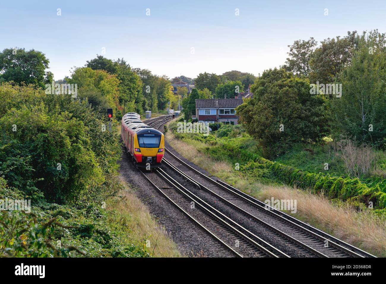 A South West Railway commuter train passing through a rural urban area ...