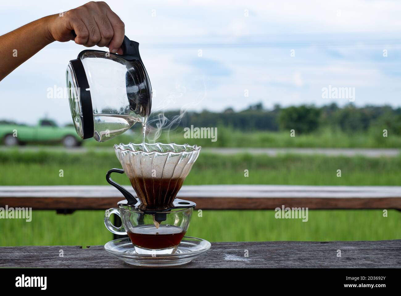 Woman handhold a coffee pot and drop to the dropper glass on the drip ...