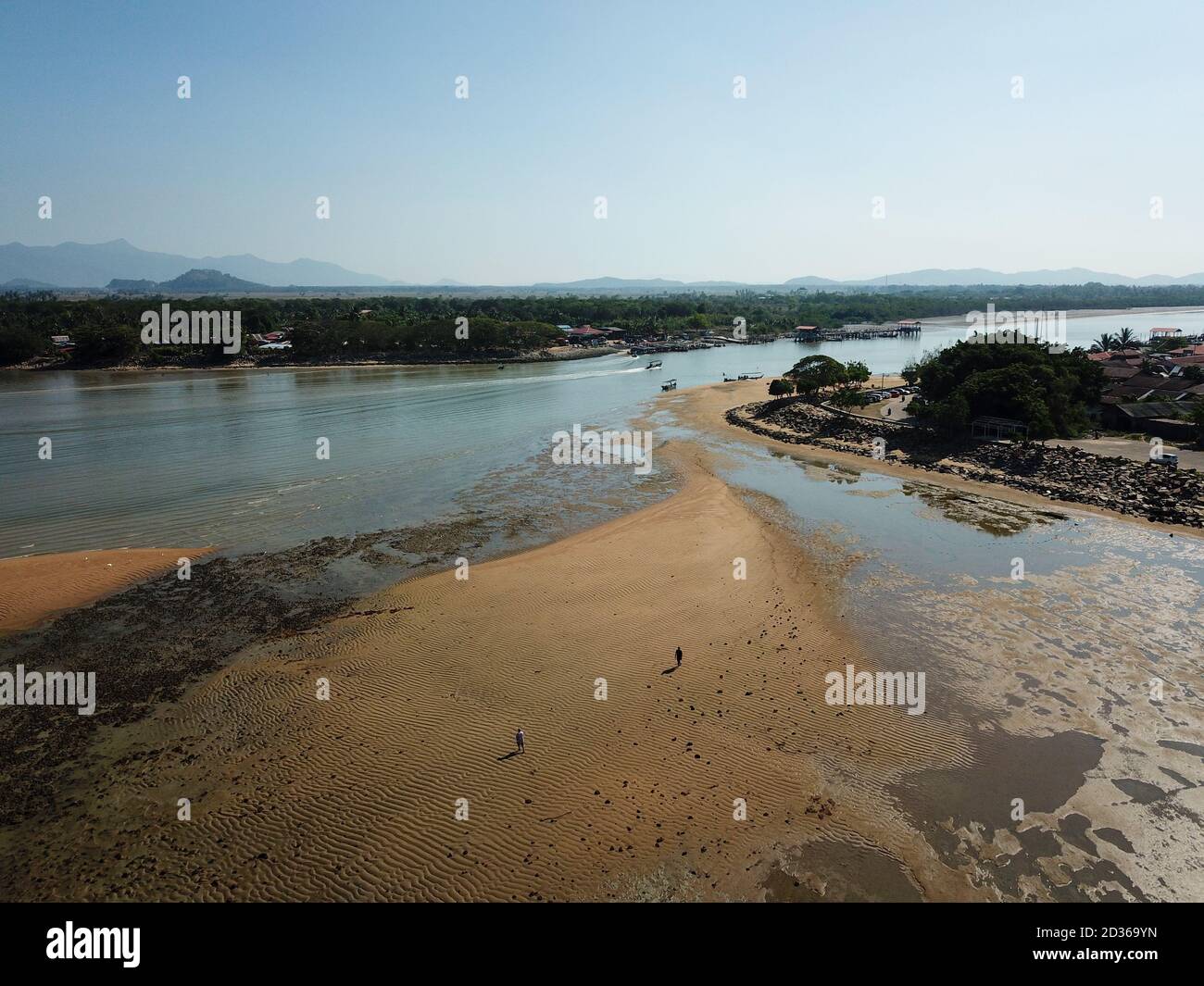 Two local walk at the muddy land near seashore during low tide season ...