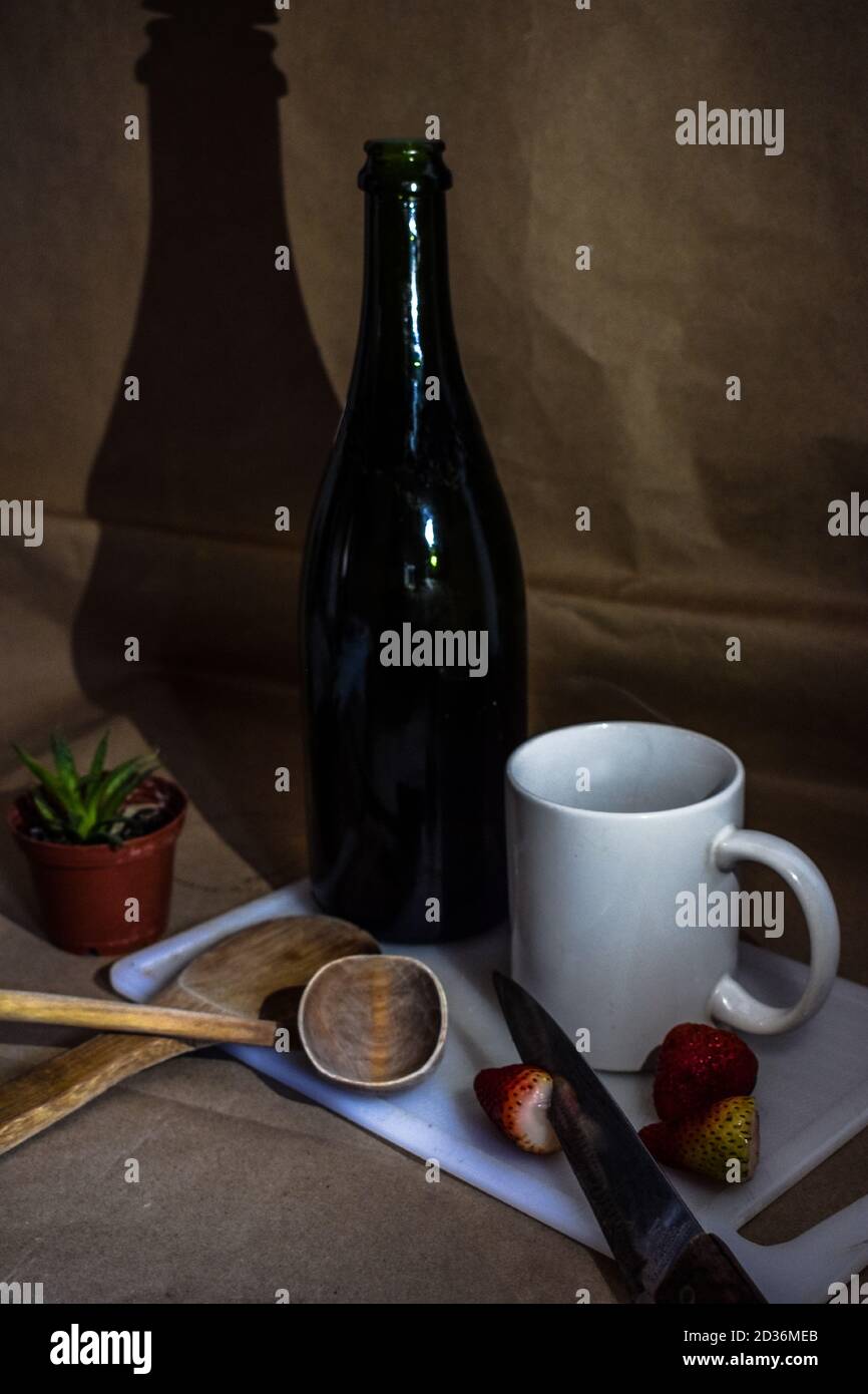 Fresh strawberries, knife, chopping board, mug, wooden spatula, bottle ...