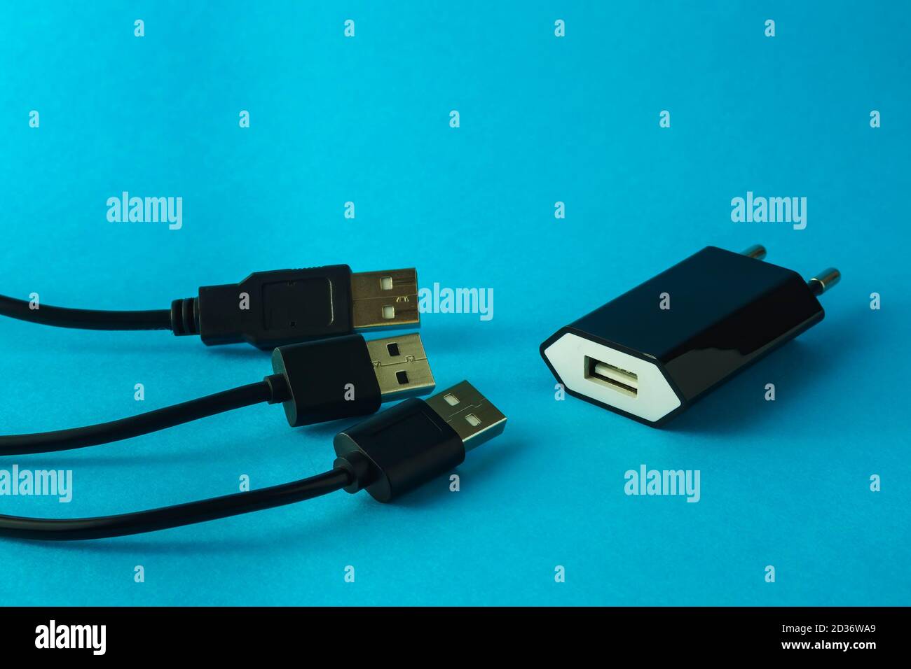 Black adapter with one usb-port and three usb cables on blue background ...