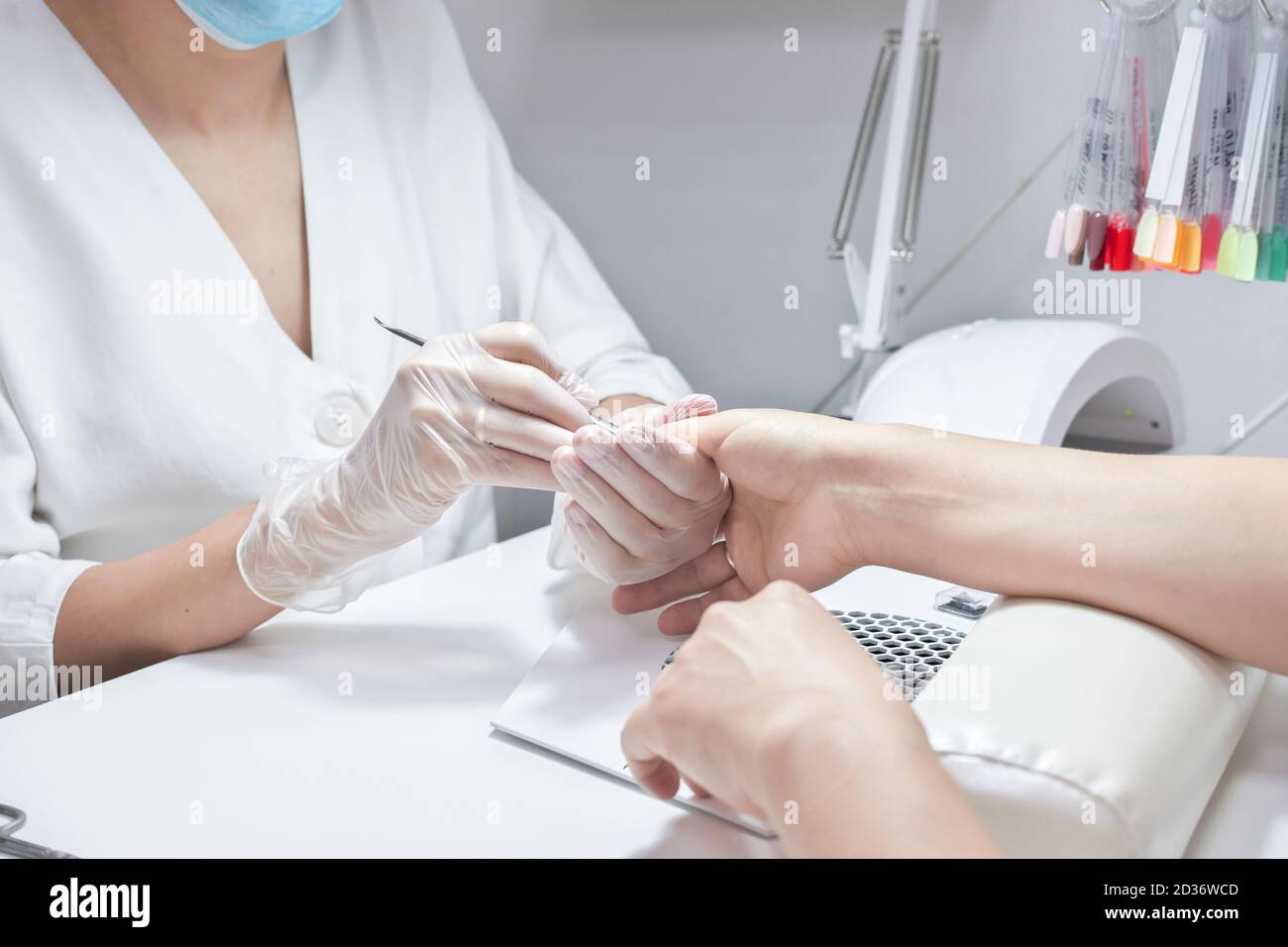 professional manicurist pushing cuticle on female hand with pushing ...