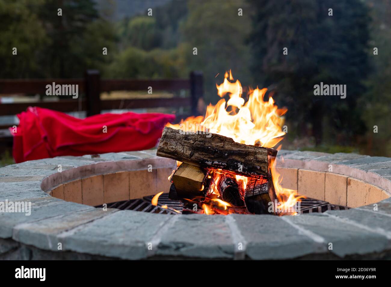 outdoor fireplace with a bright flame in a fire pit and autumn forest ...