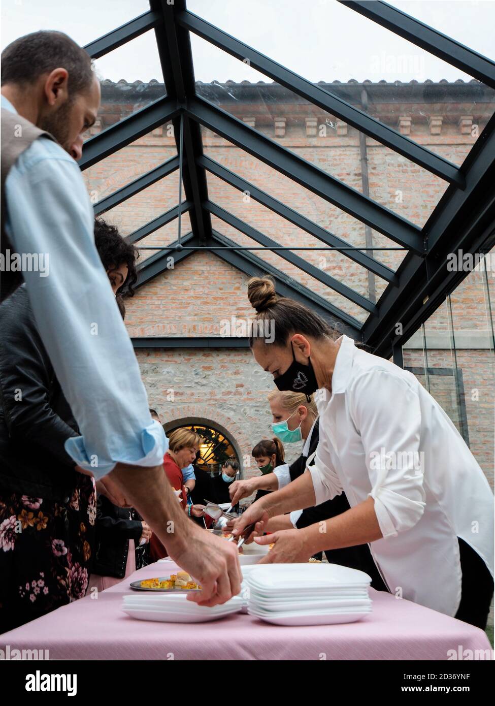 People and catering staff wearing face mask for covid protection at a ...