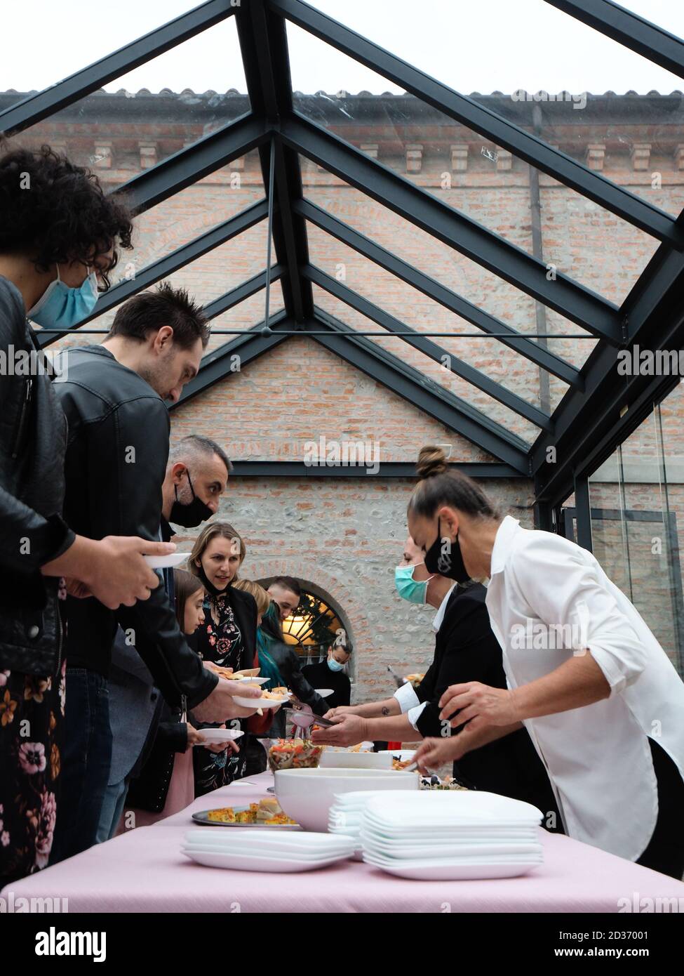 People and catering staff wearing face mask for covid protection at a ...