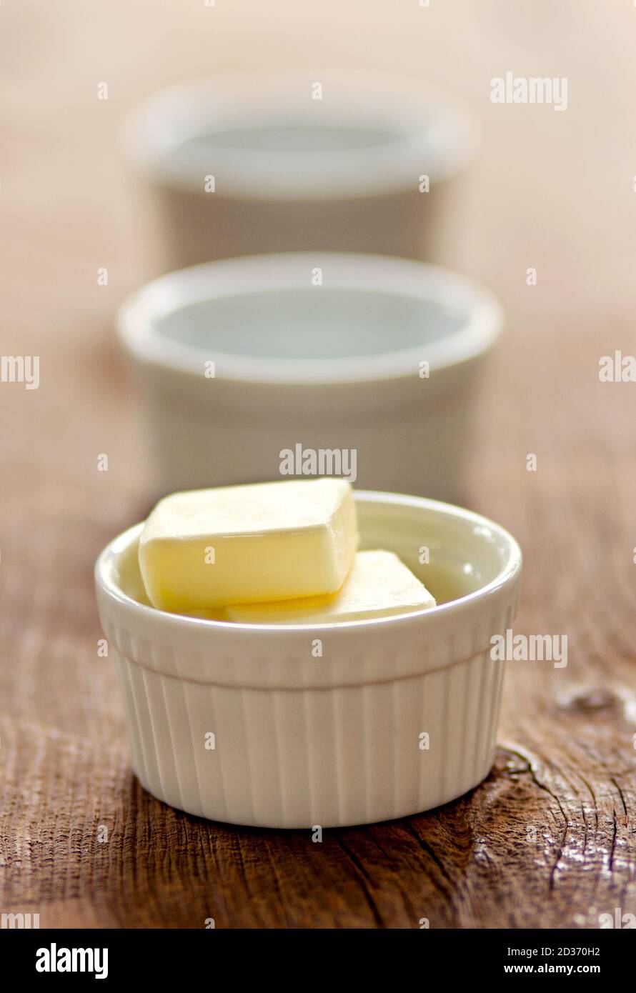 Cubes of butter in white ramekins on wood tabletop Stock Photo - Alamy