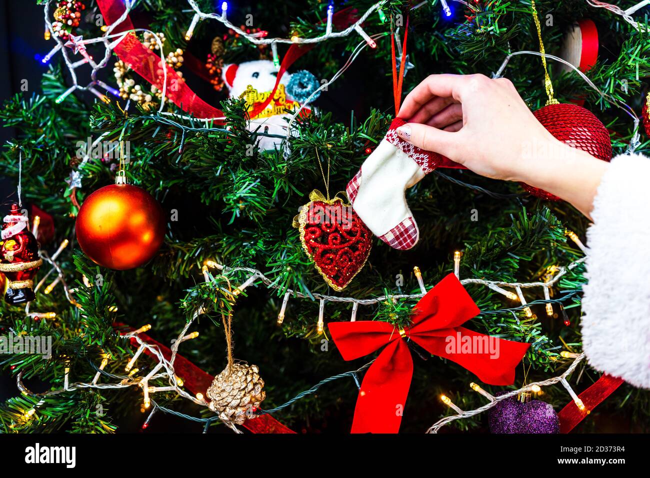 Decorating Christmas tree, hand putting Christmas decorations on fir ...