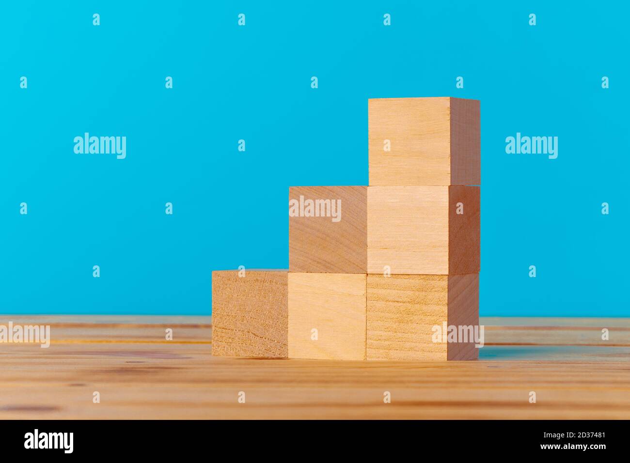 Stacked wooden blocks on wooden desk against blue background Stock ...