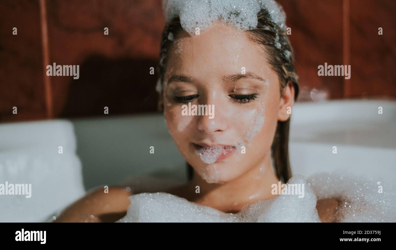 Shallow focus of a beautiful young woman covered in bubbles and enjoying a bubble bath in a tub ...