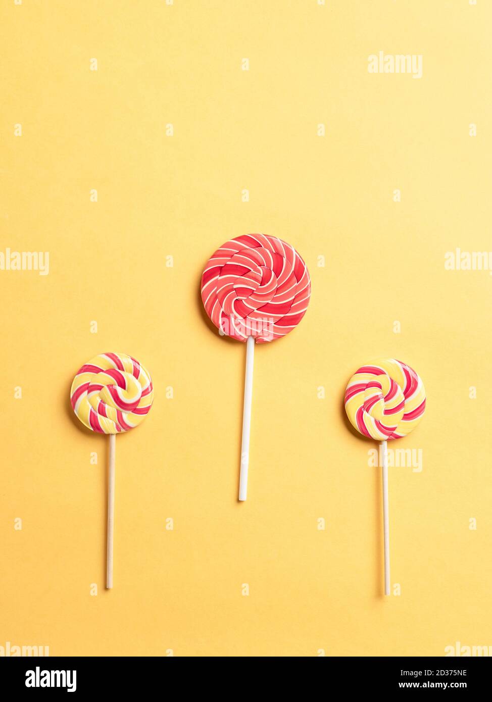 Three lollipops on a yellow background Stock Photo - Alamy