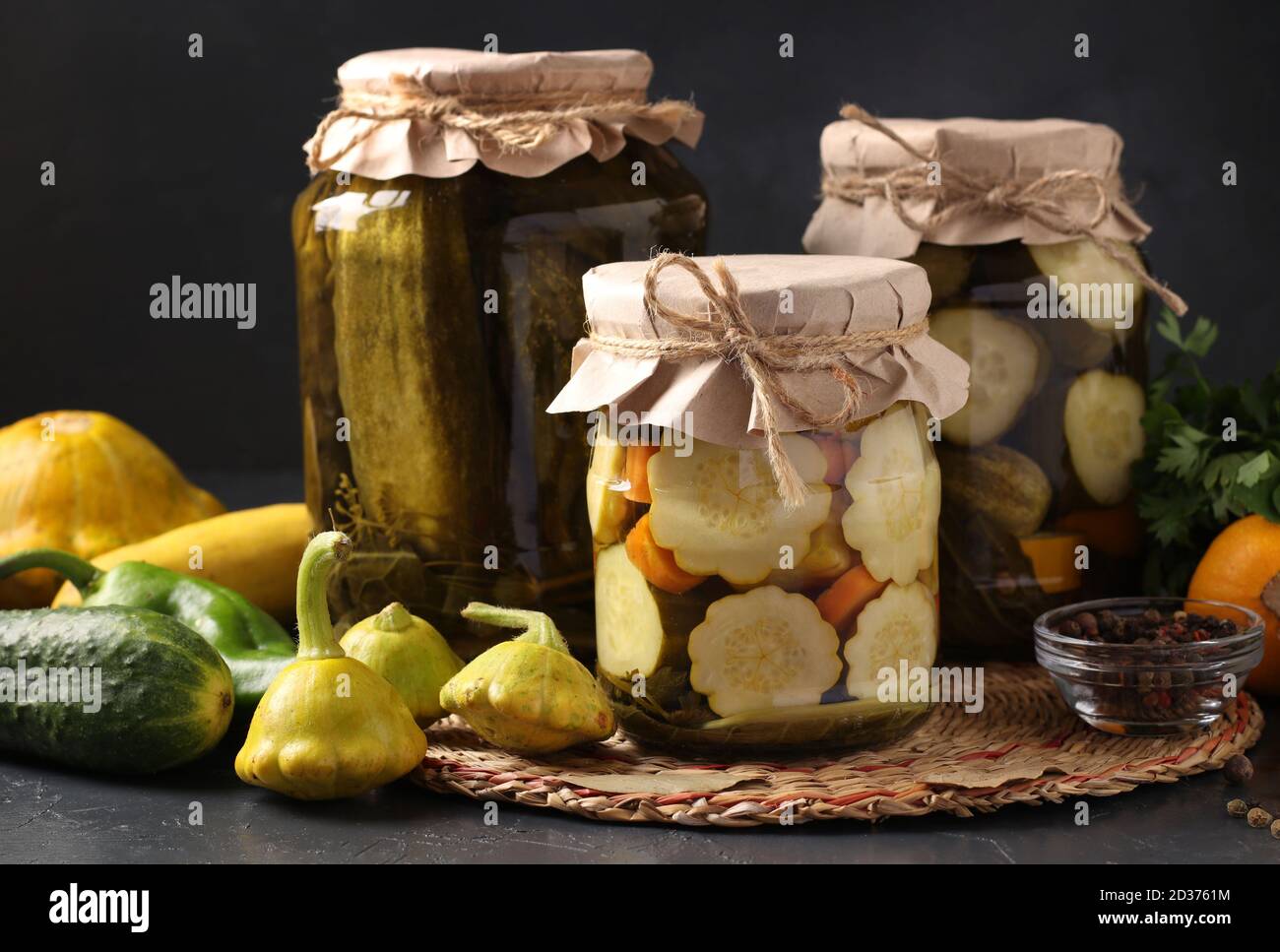 Homemade pickled patissons, cucumbers and zucchini on dark background ...