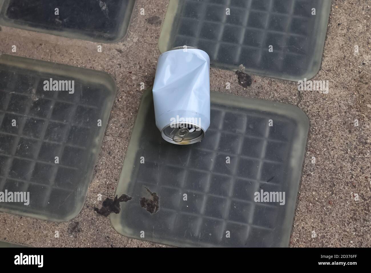 Gray crumpled can thrown on a sidewalk Stock Photo - Alamy
