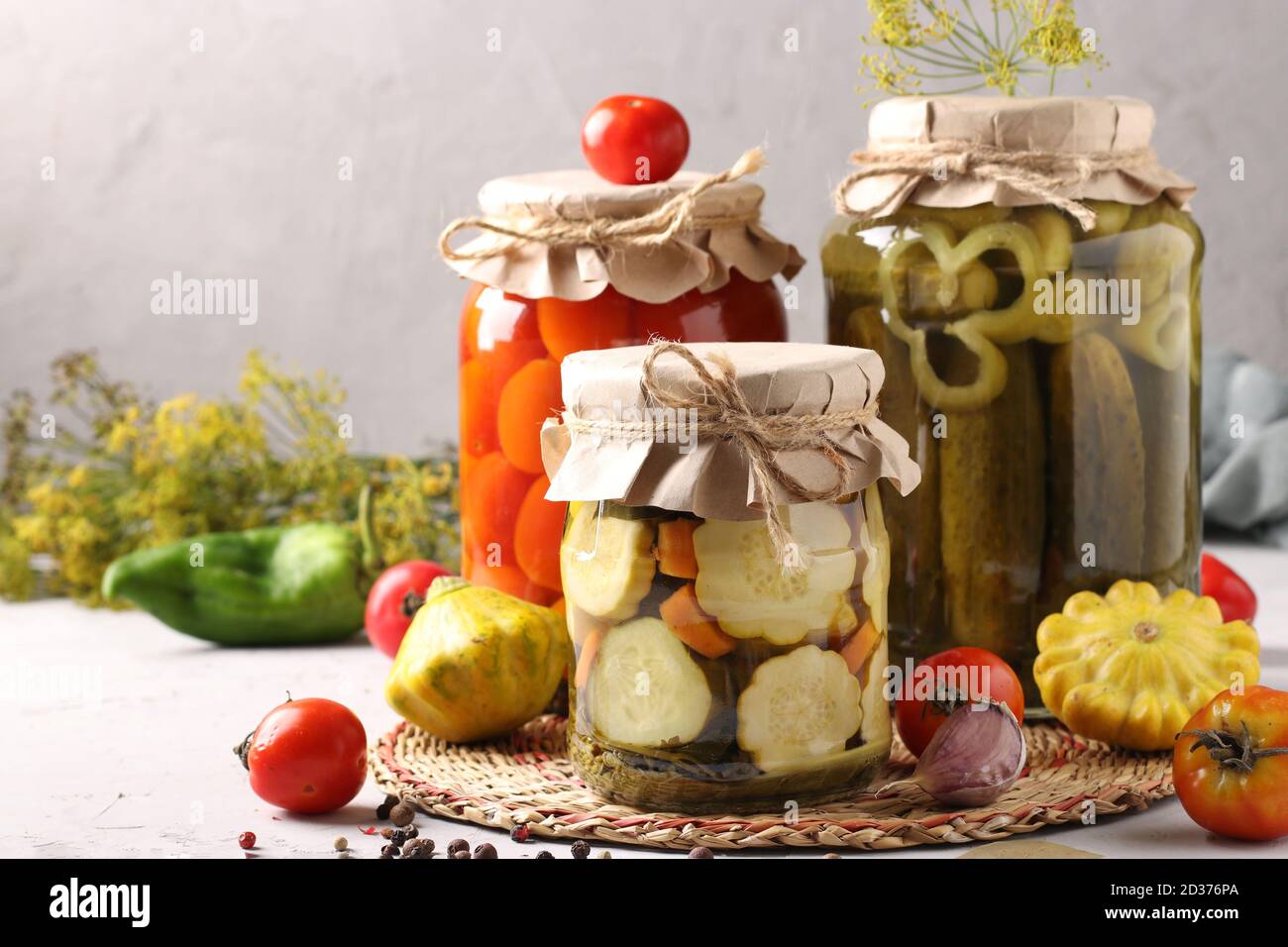 Homemade pickled patissons, tomatoes and cucumbers on grey background ...