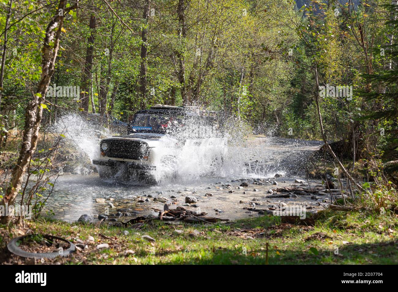 Off-road vehicle with tourists crossing a mountain river Stock Photo ...
