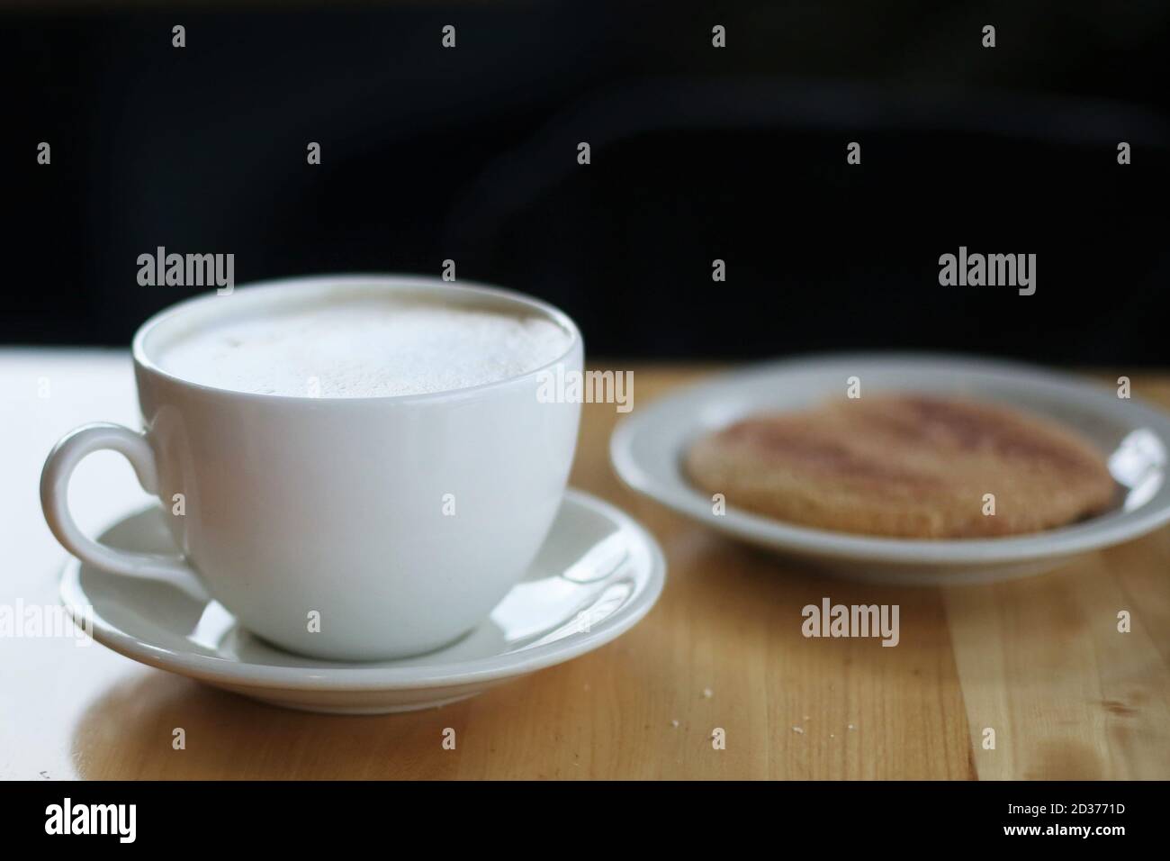 A frothy hot mocha in a cup and a saucer with a snickerdoodle cookie ...