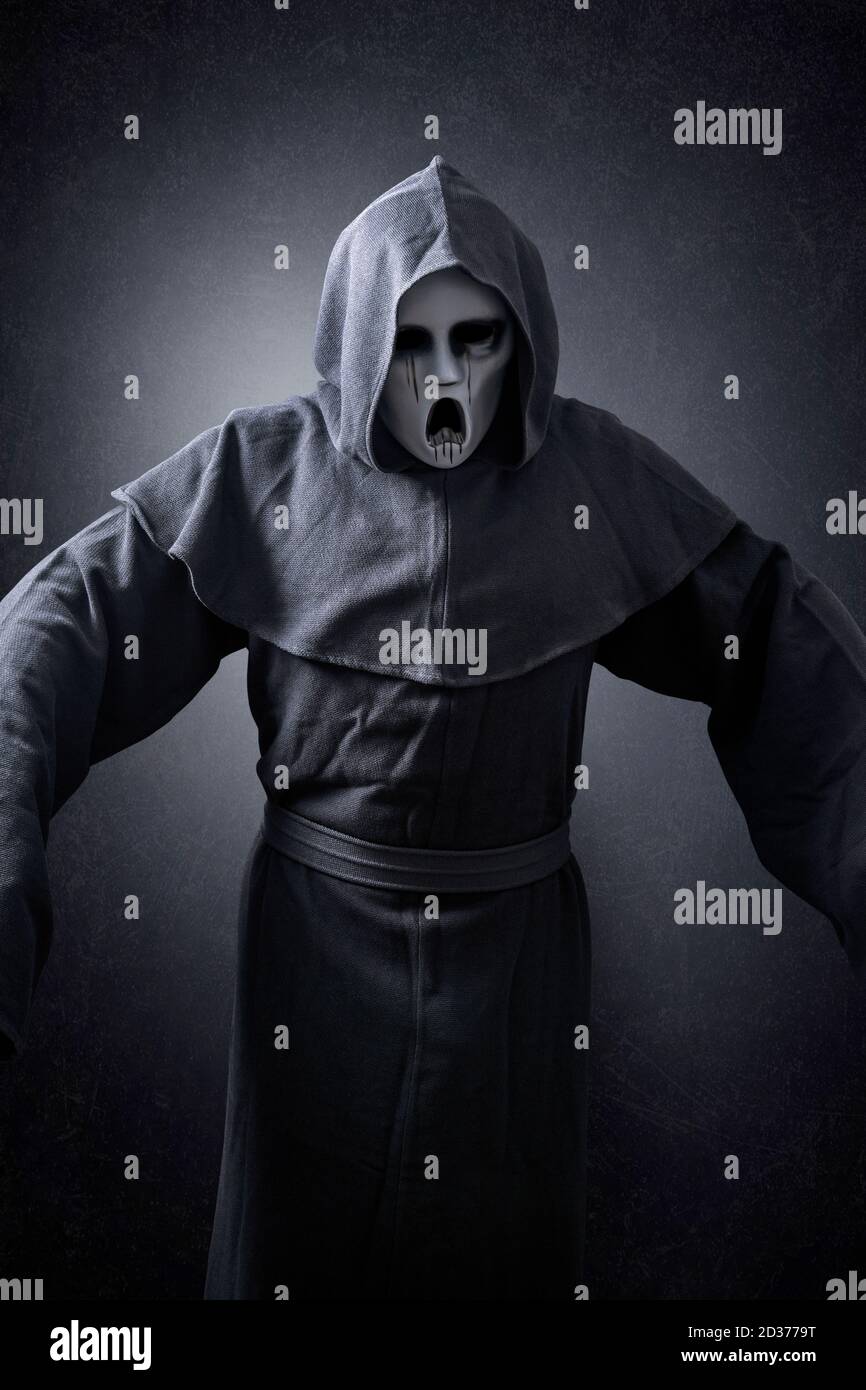 Scary figure with mask in hooded cloak in the dark Stock Photo - Alamy