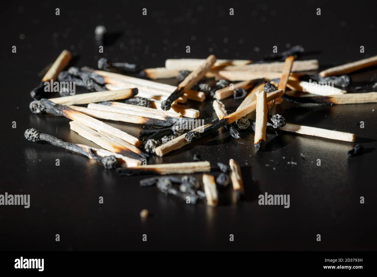 Used wooden matches with the remains of ashes on a black board ...