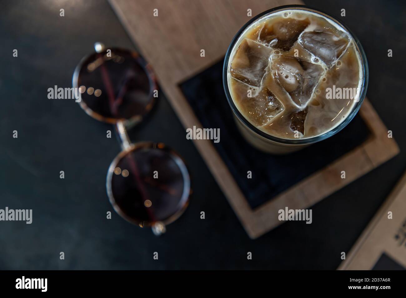 Cold coffee in a tall glass with ice cubes on wooden background. Cold ...