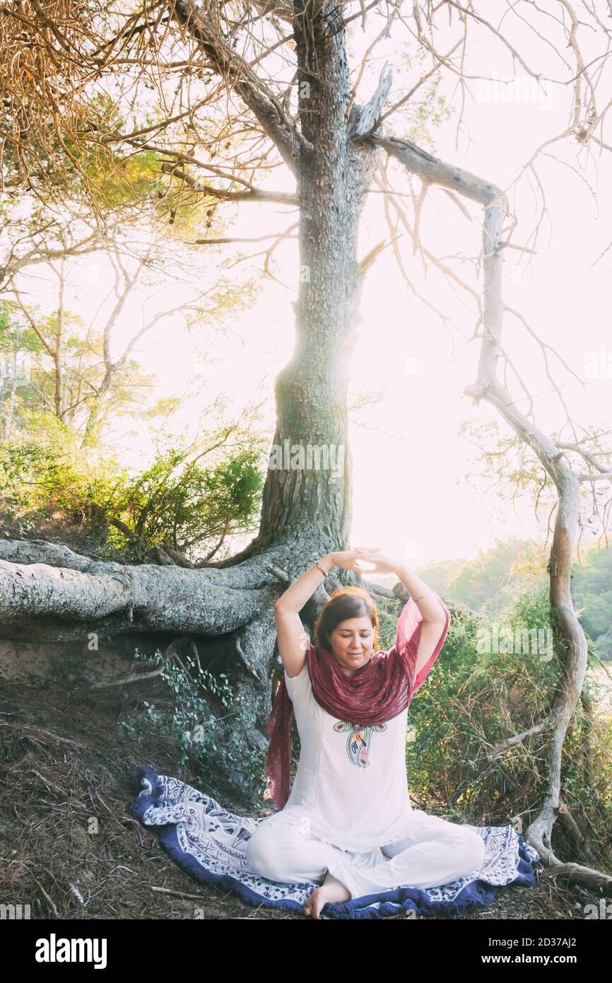 Woman meditating under tree hi-res stock photography and images - Alamy